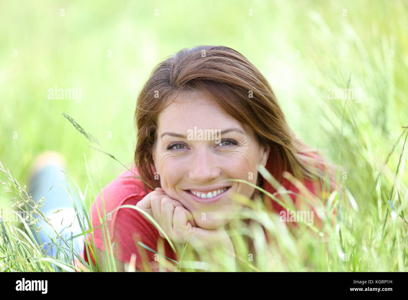 Beautiful smiling woman laying in country field Stock Photo - Alamy