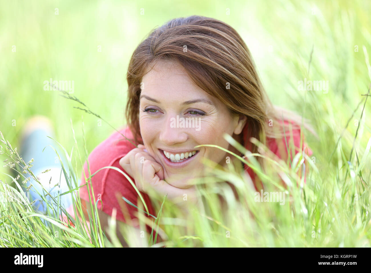 Beautiful smiling woman laying in country field Stock Photo - Alamy