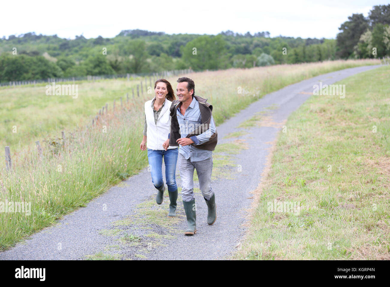 Cheerful couple of farmers running in countryside Stock Photo - Alamy