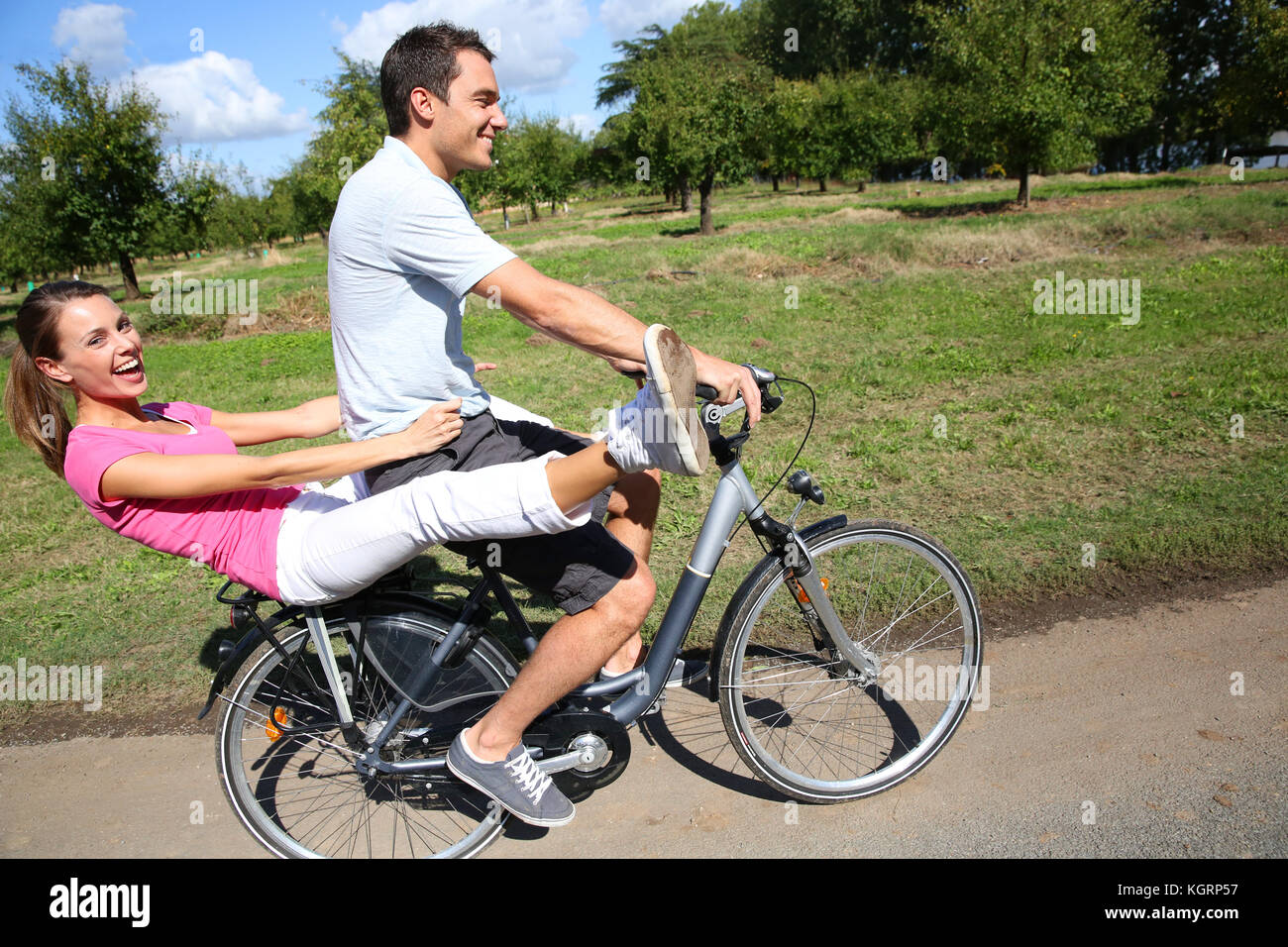 Cheerful young couple riding bikes in countryside Stock Photo - Alamy