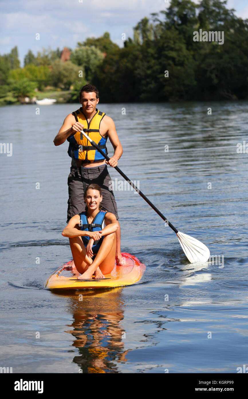 Couple riding stand-up-paddle on river Stock Photo - Alamy