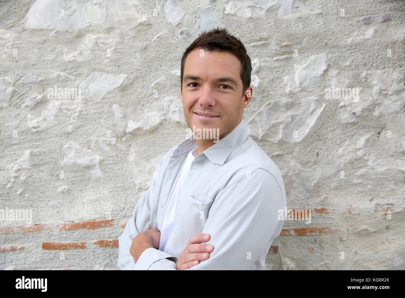 Smiling handsome man leaning on wall Stock Photo - Alamy