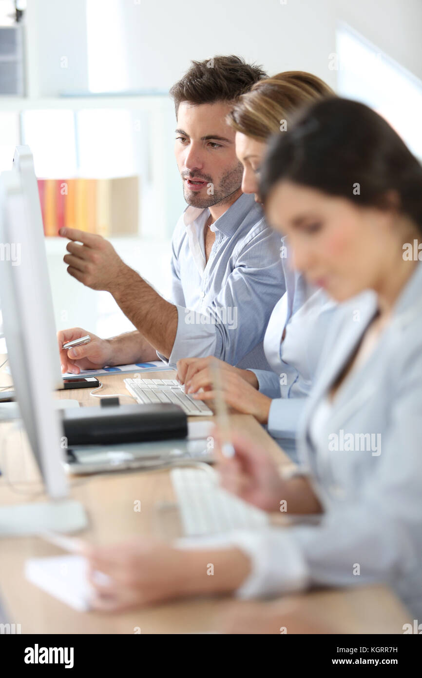 Workteam in office working on desktop computer Stock Photo - Alamy