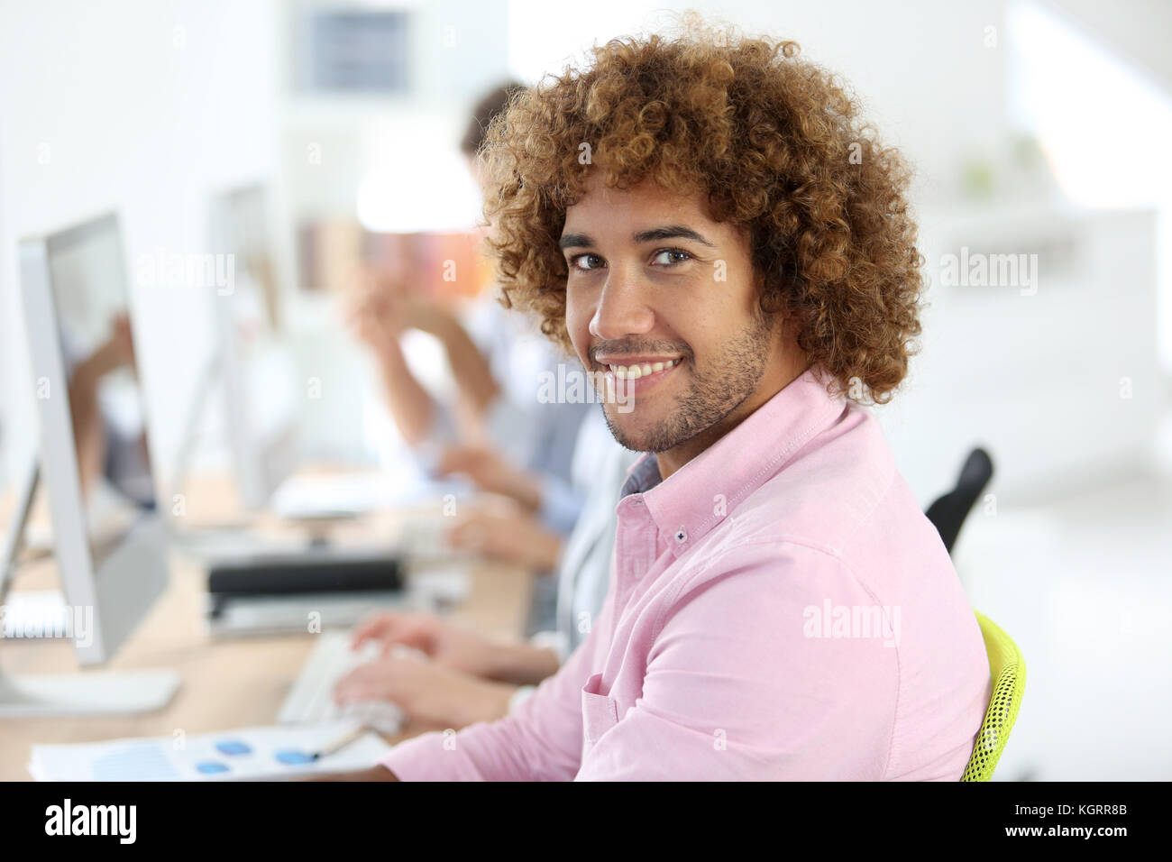 Smiling office-worker sitting at desk Stock Photo - Alamy