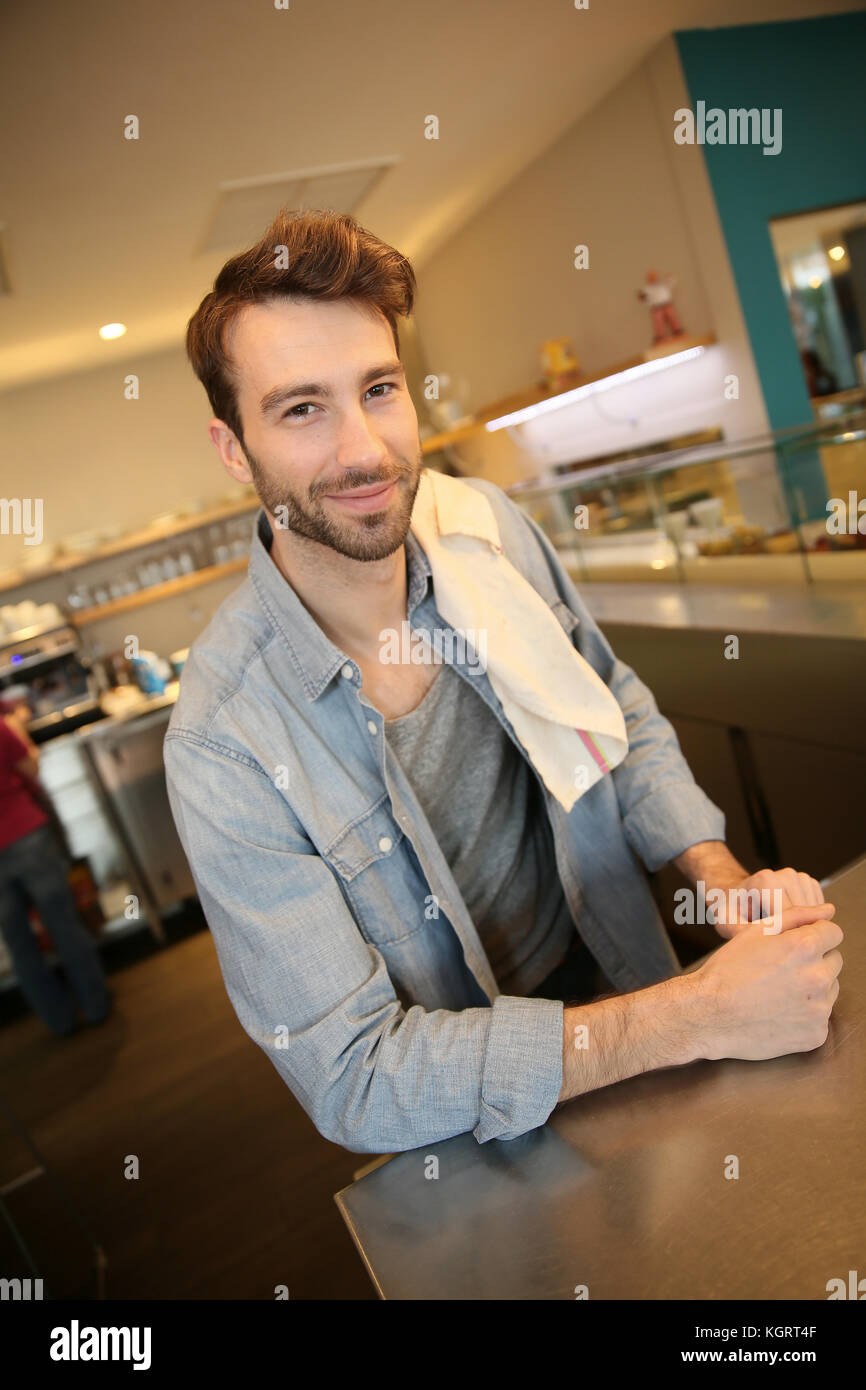 Smiling waiter in coffee shop standing by counter Stock Photo - Alamy