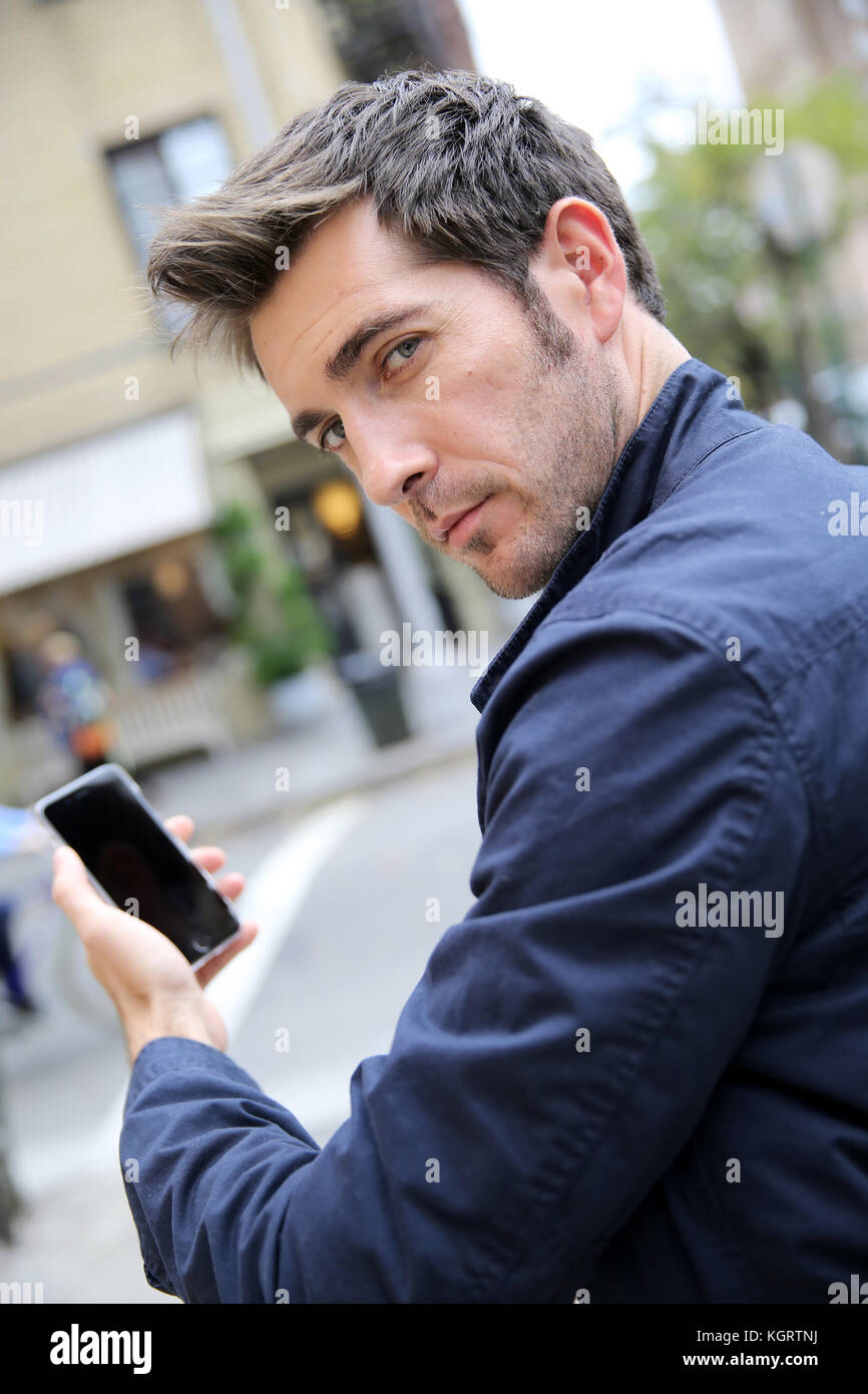 Man in city street showing smartphone screen Stock Photo - Alamy