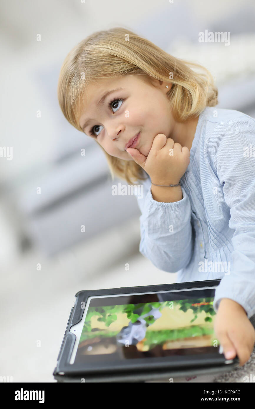 Little girl using tablet with thoughtful expresssion Stock Photo - Alamy