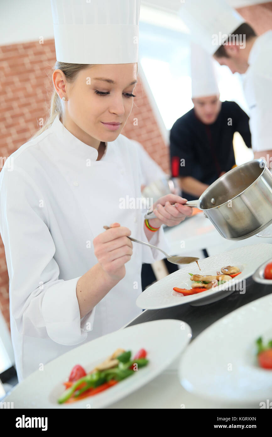 Young woman in cooking class pouring sauce on plate Stock Photo - Alamy