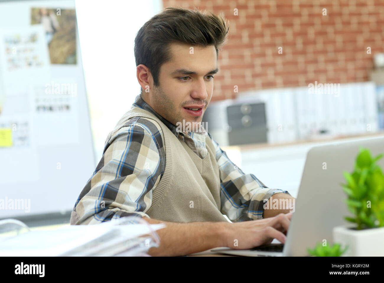 Young man working on laptop computer in office Stock Photo - Alamy