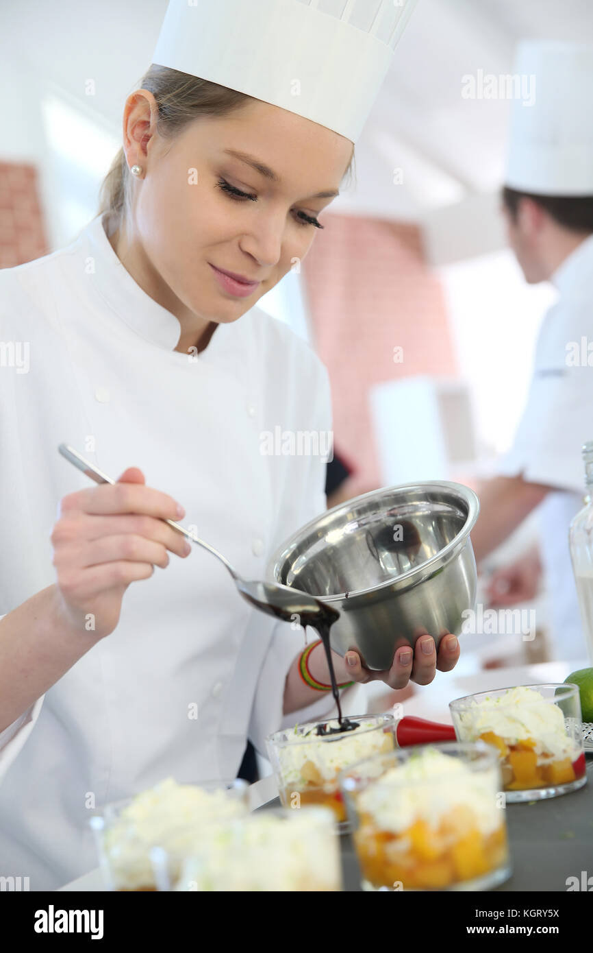 Pastry cook student pouring chocolate sauce on dessert Stock Photo - Alamy