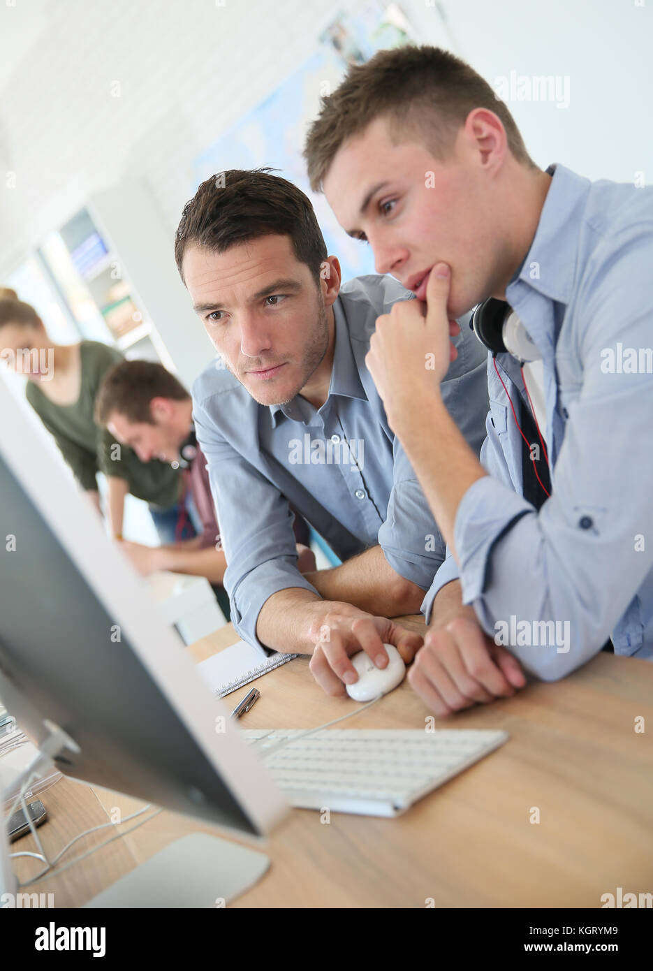 Teacher with student working on desktop Stock Photo - Alamy
