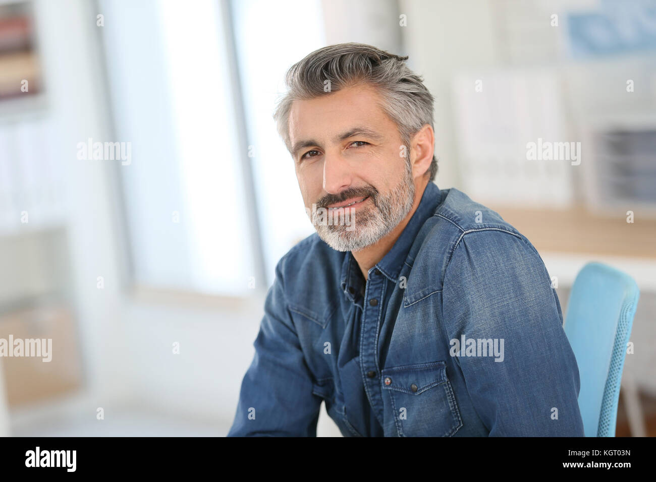 Smiling teacher sitting at desk in university office Stock Photo - Alamy