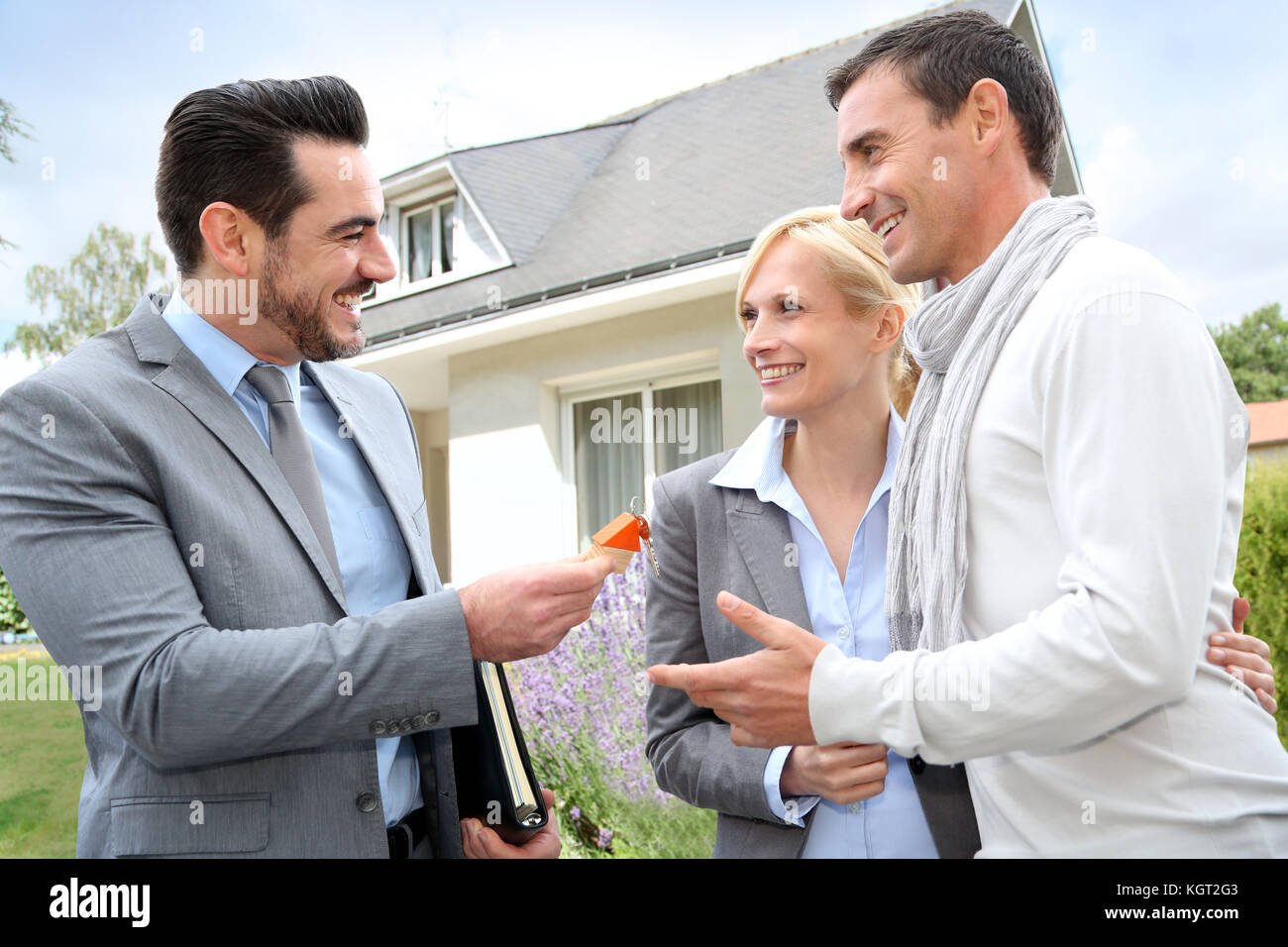 Salesman giving home keys to property owners Stock Photo - Alamy