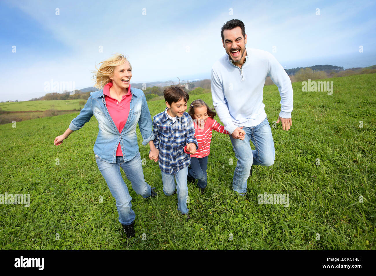 Family of four running together in natural landscape Stock Photo - Alamy