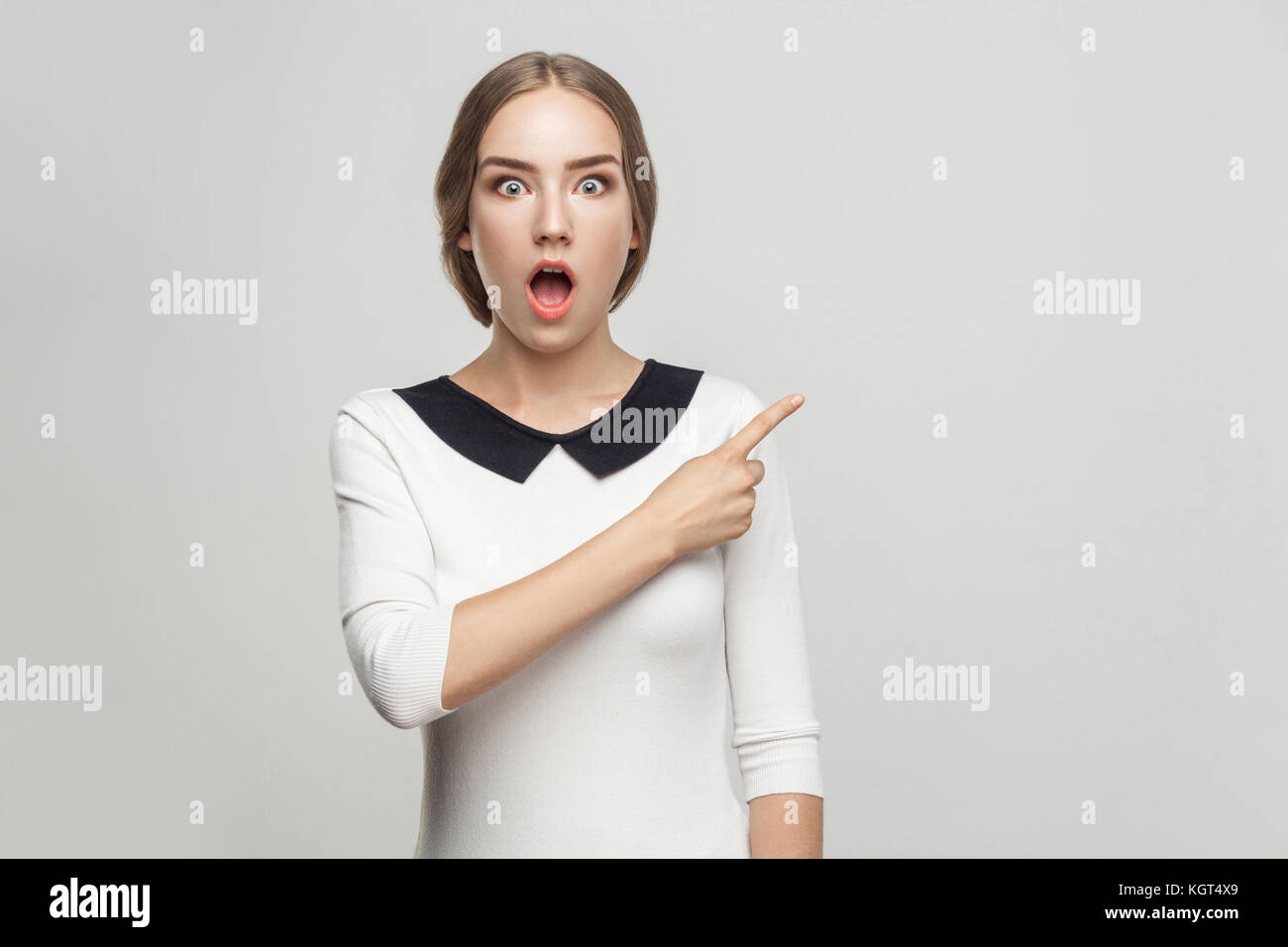 Boss pointing finger at copy space, and looking at camera with shocked ...