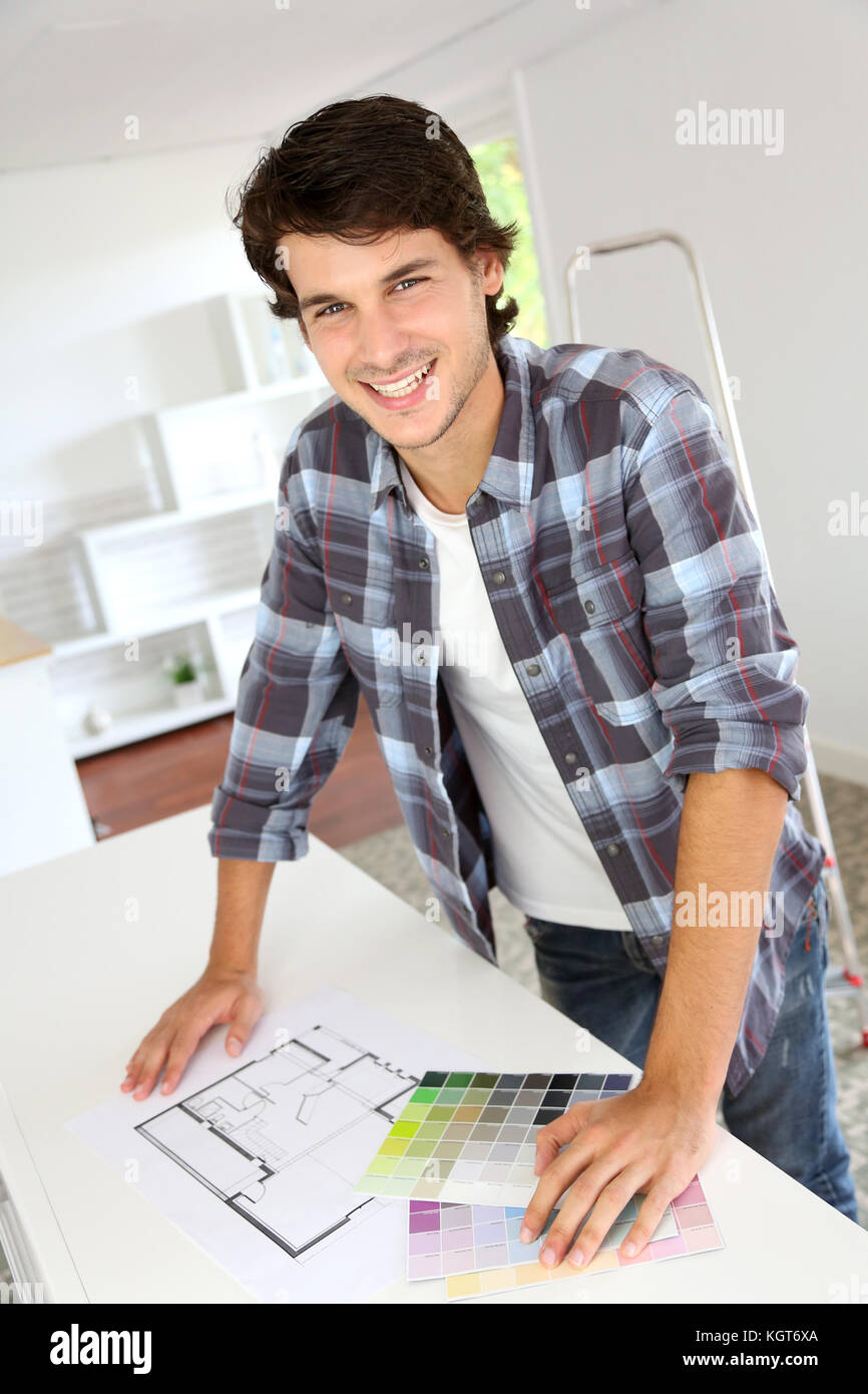 Cheerful young man looking at colours sample for new home Stock Photo ...