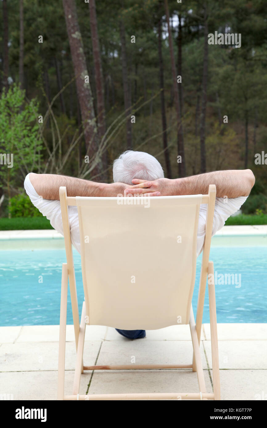 Senior man relaxing in deck chair by a pool Stock Photo - Alamy