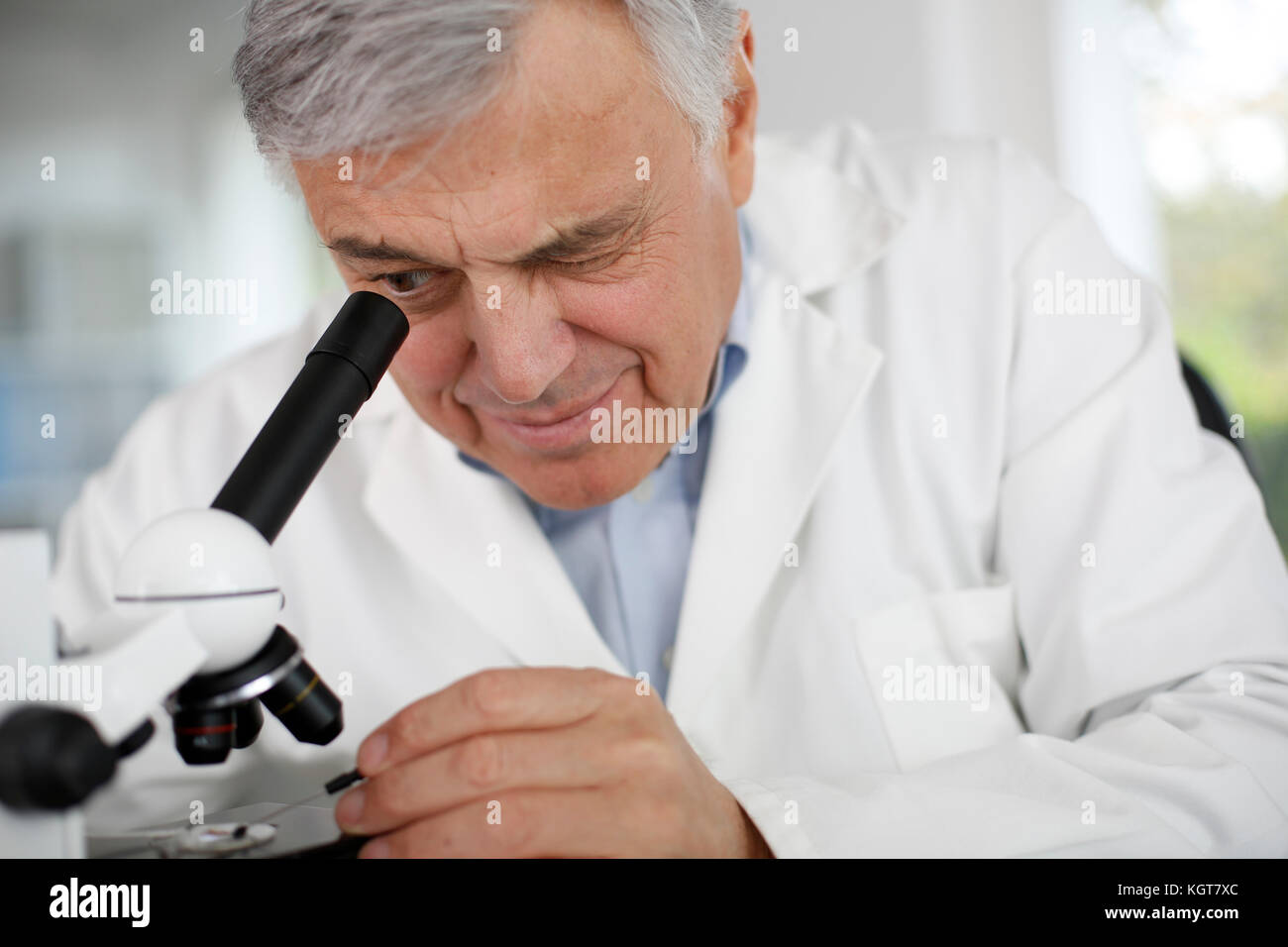 Scientist in lab looking through microscope lens Stock Photo - Alamy