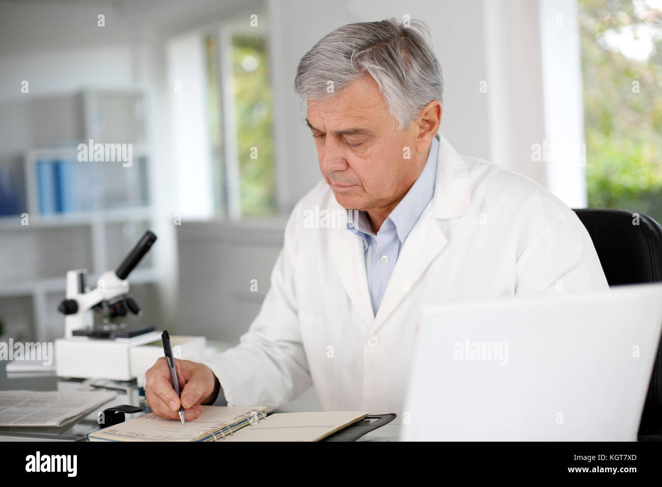 Doctor in biology writing report on agenda Stock Photo - Alamy
