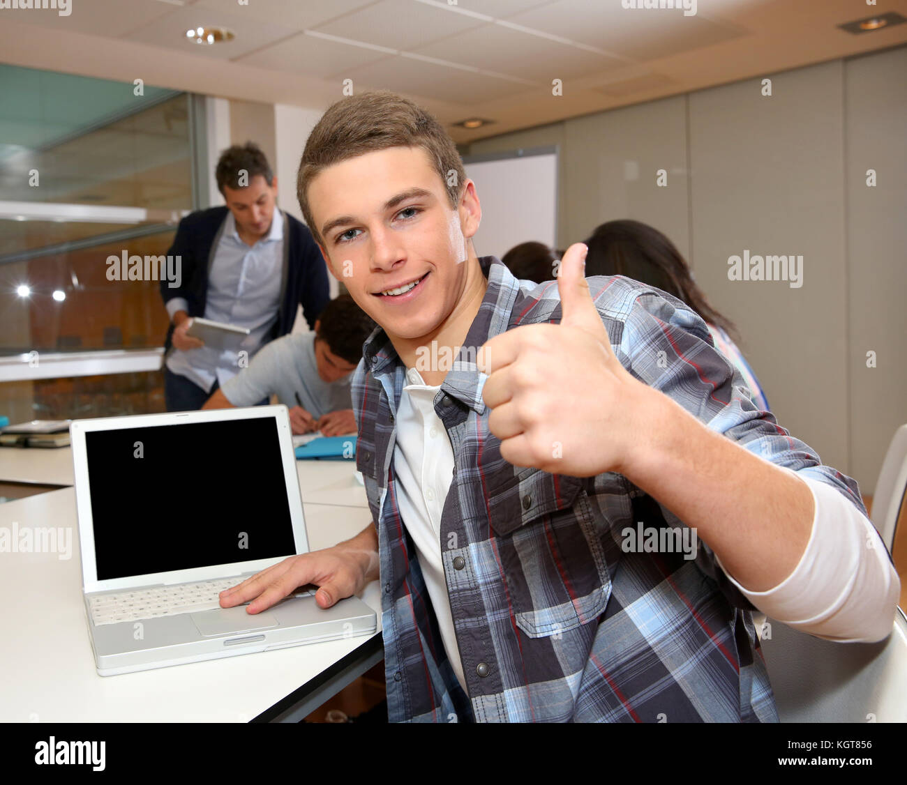 Student with laptop showing thumb up Stock Photo - Alamy