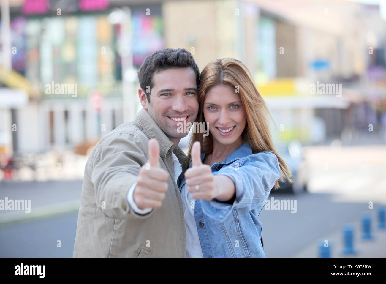 Happy couple with thumbs up in town Stock Photo - Alamy
