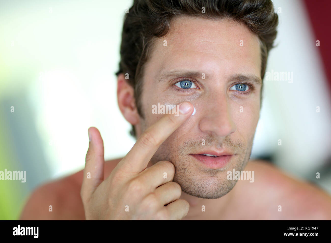 Handsome man applying moisturizing cream Stock Photo - Alamy