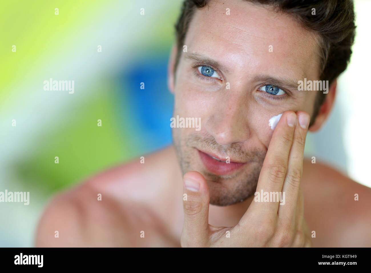 Handsome man applying moisturizing cream Stock Photo - Alamy