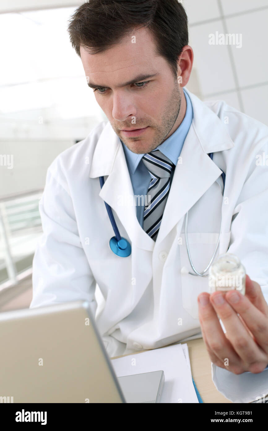 Doctor with laptop computer checking medicine composition Stock Photo ...
