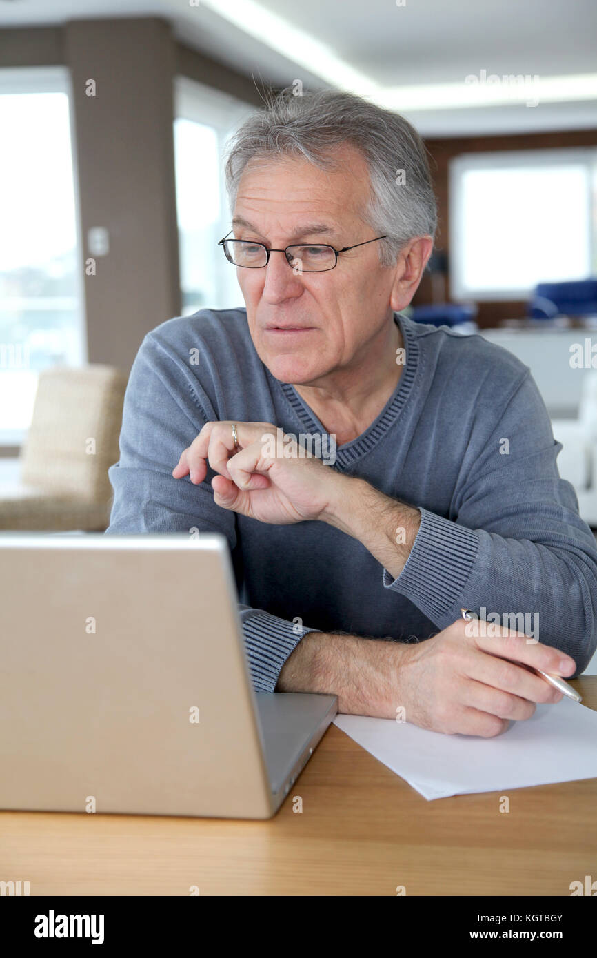Senior man at home in front of laptop computer Stock Photo - Alamy