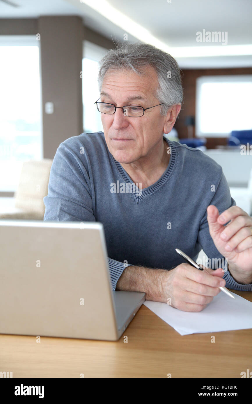 Senior man at home in front of laptop computer Stock Photo - Alamy