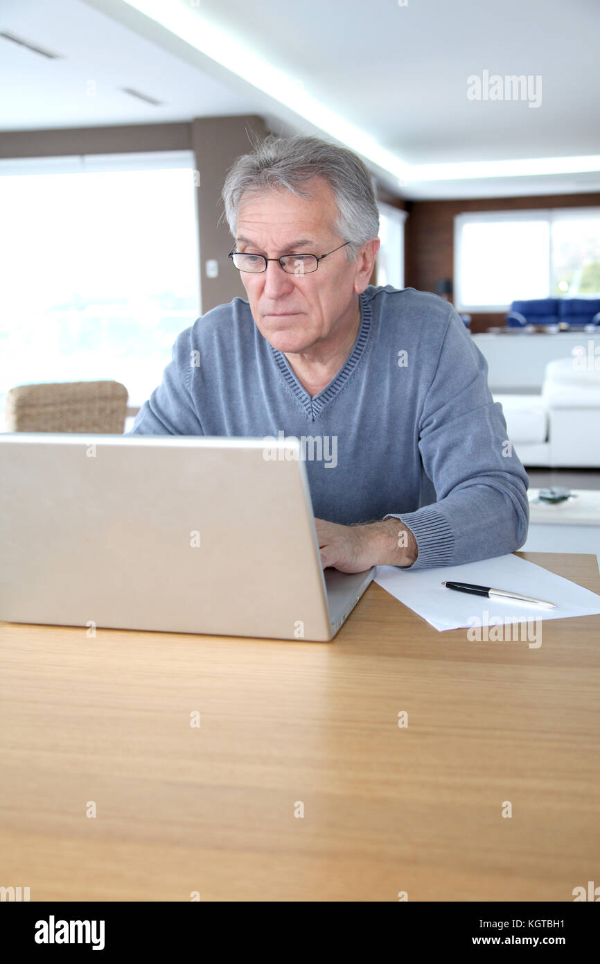 Senior man at home in front of laptop computer Stock Photo - Alamy
