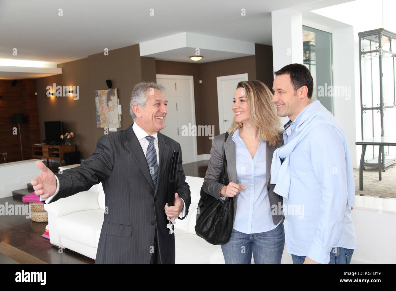 Real estate agent showing modern house to couple Stock Photo - Alamy