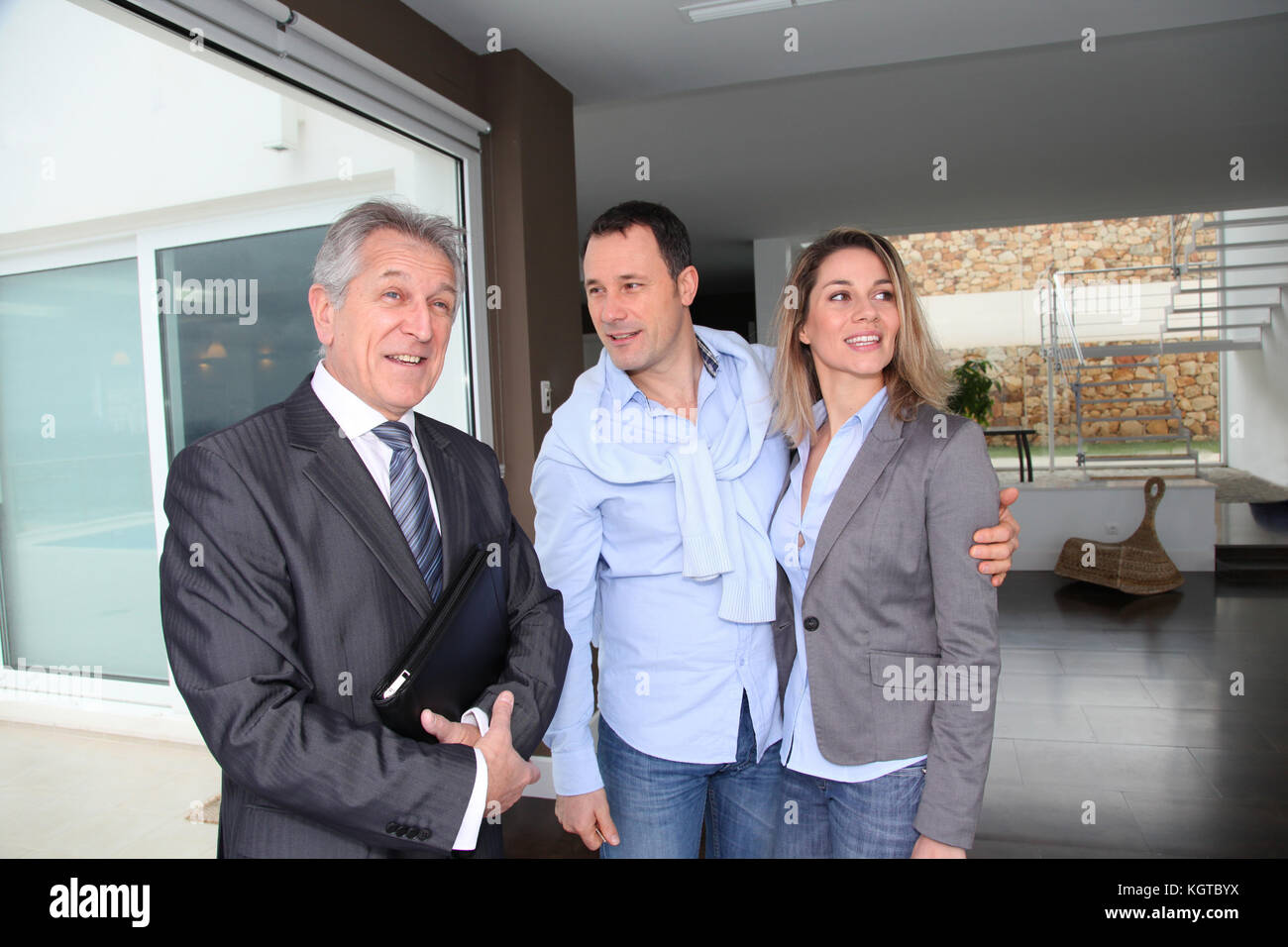 Real estate agent showing modern house to couple Stock Photo - Alamy