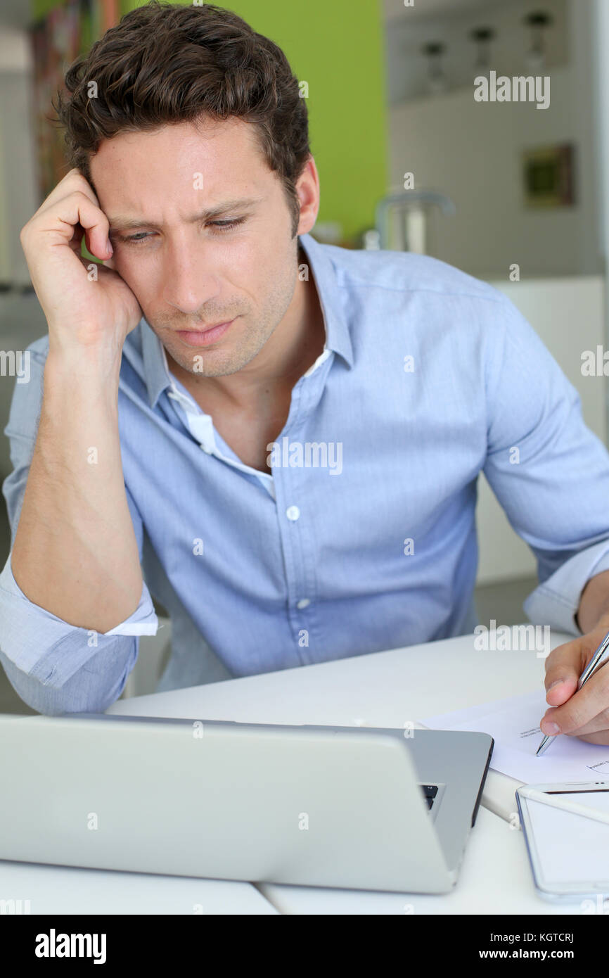 Man with doubtful look in front of laptop Stock Photo - Alamy