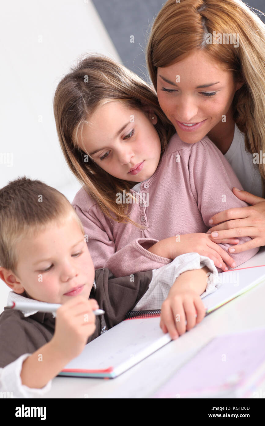 Woman helping kids with homework Stock Photo - Alamy