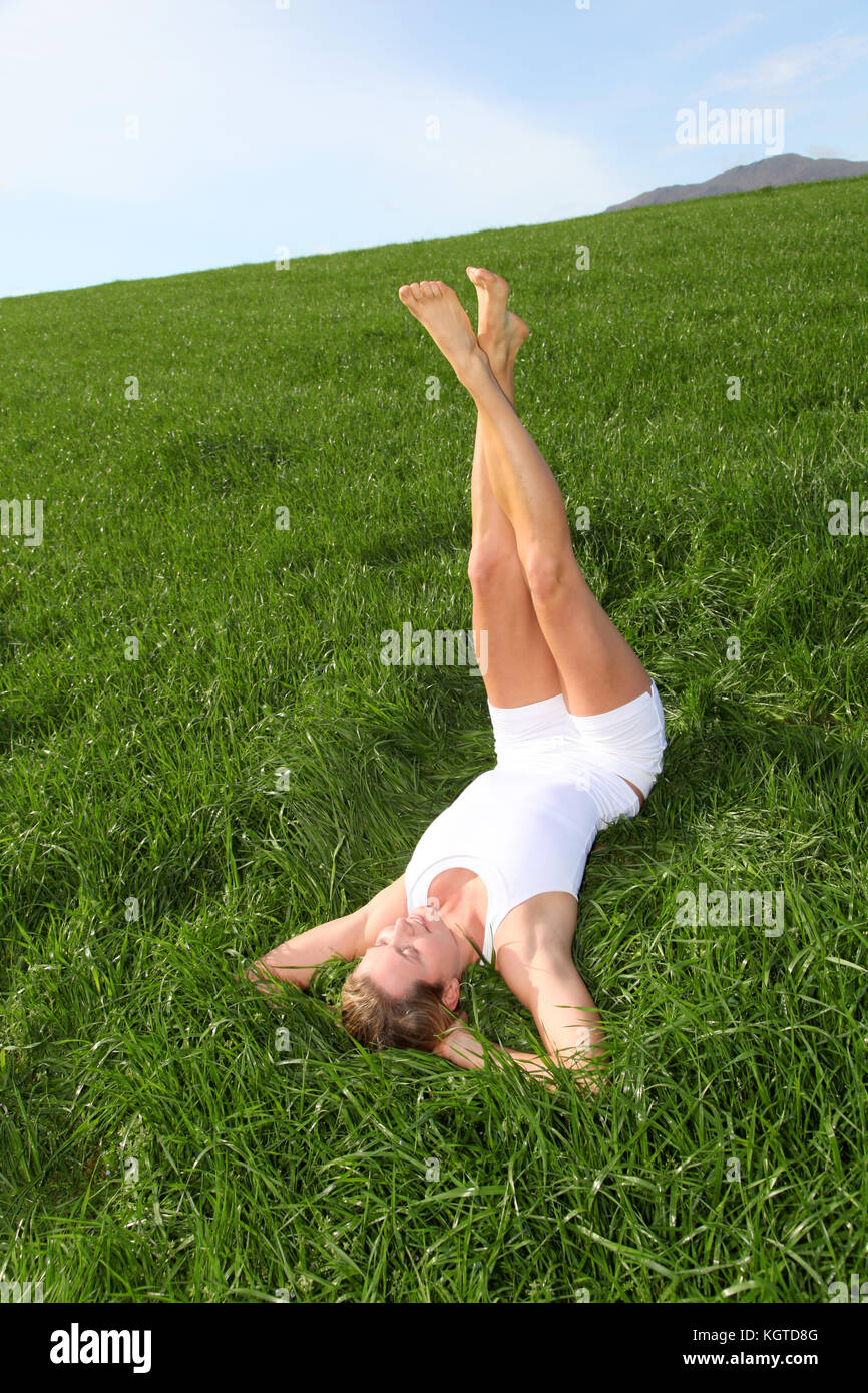 Woman laying down green field with legs up Stock Photo - Alamy