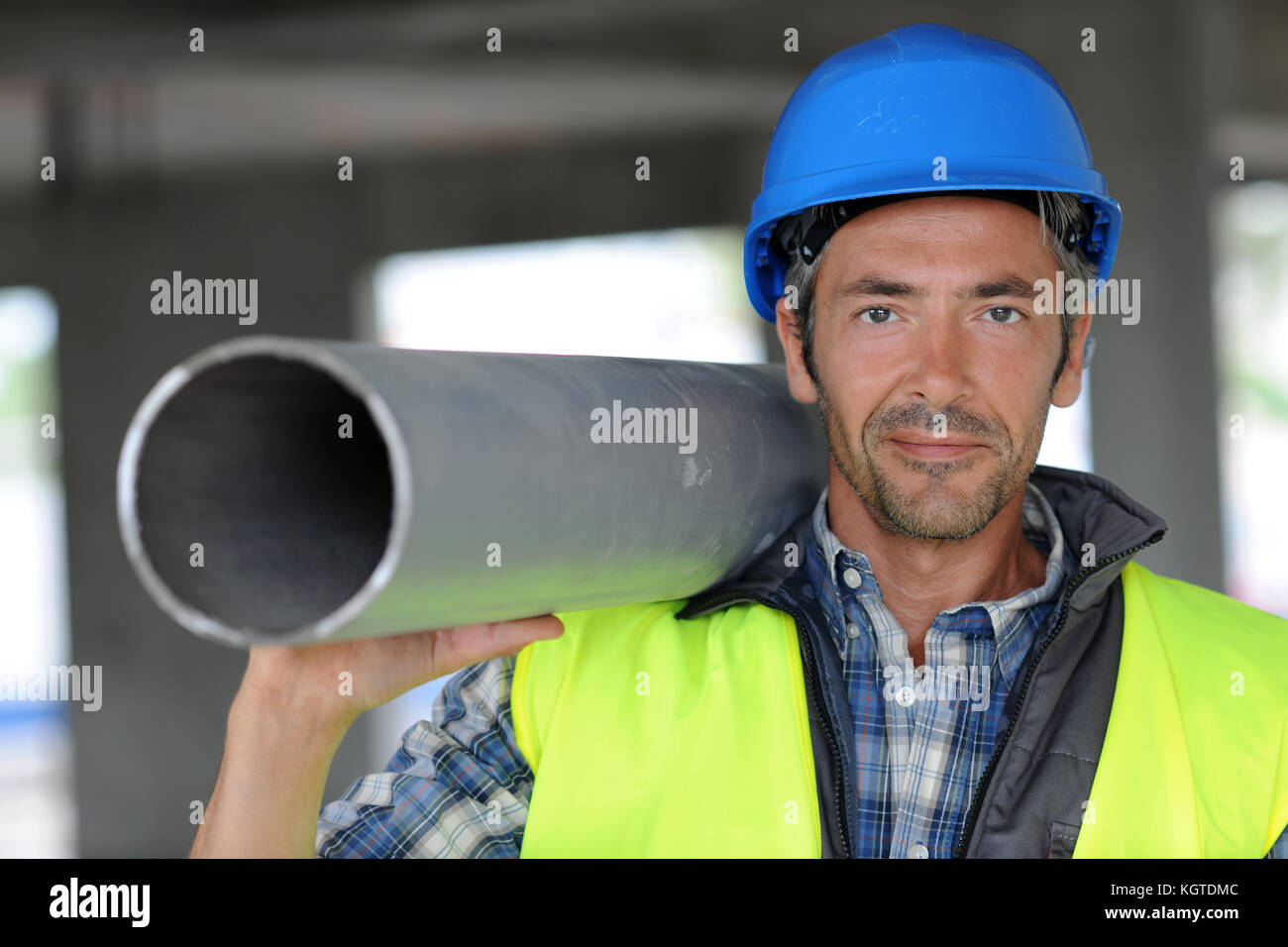 Construction worker on site holding pipe Stock Photo - Alamy