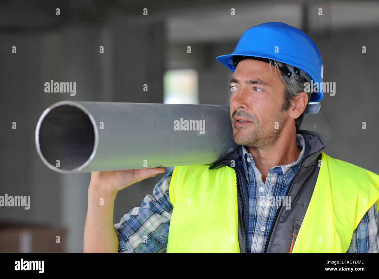 Construction worker on site holding pipe Stock Photo - Alamy