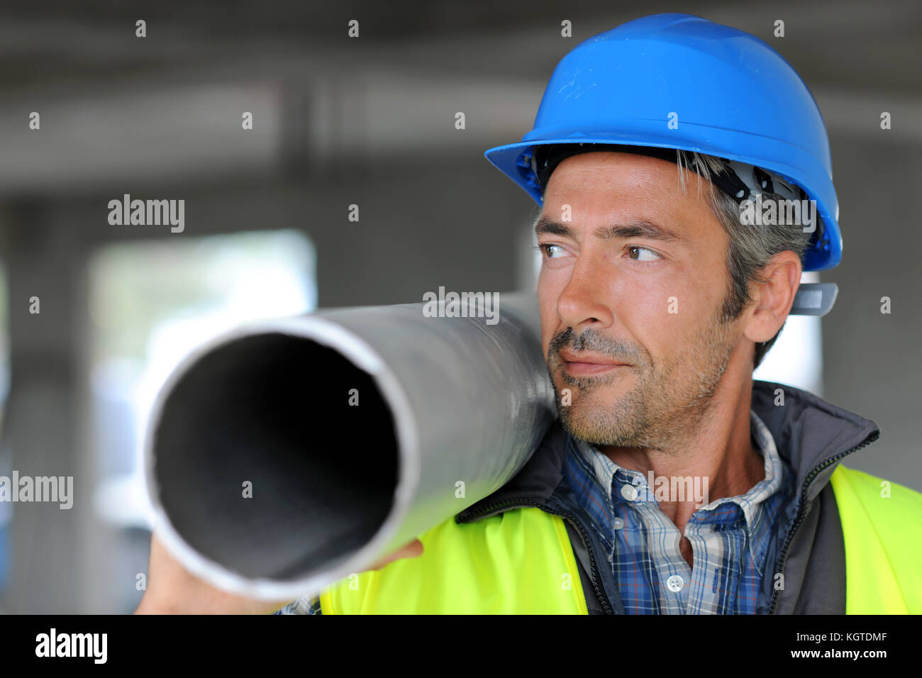 Construction worker on site holding pipe Stock Photo - Alamy