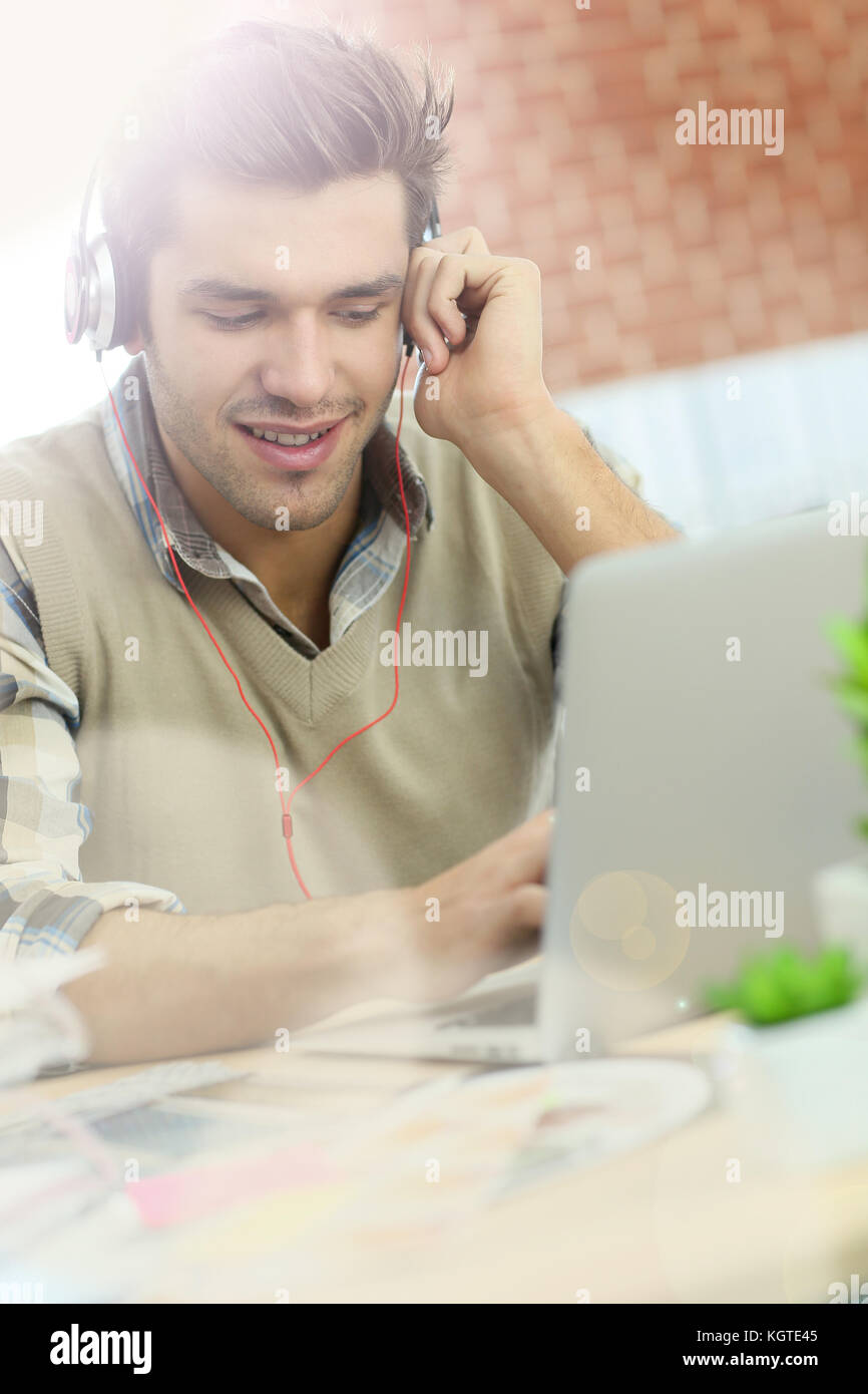 Young office worker using headphones in front of laptop Stock Photo - Alamy