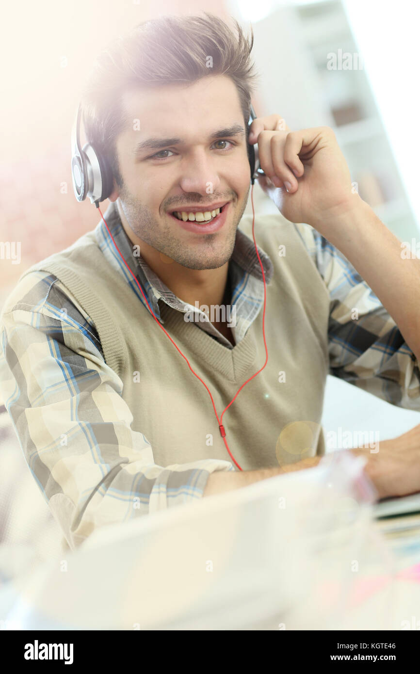 Young office worker using headphones in front of laptop Stock Photo - Alamy