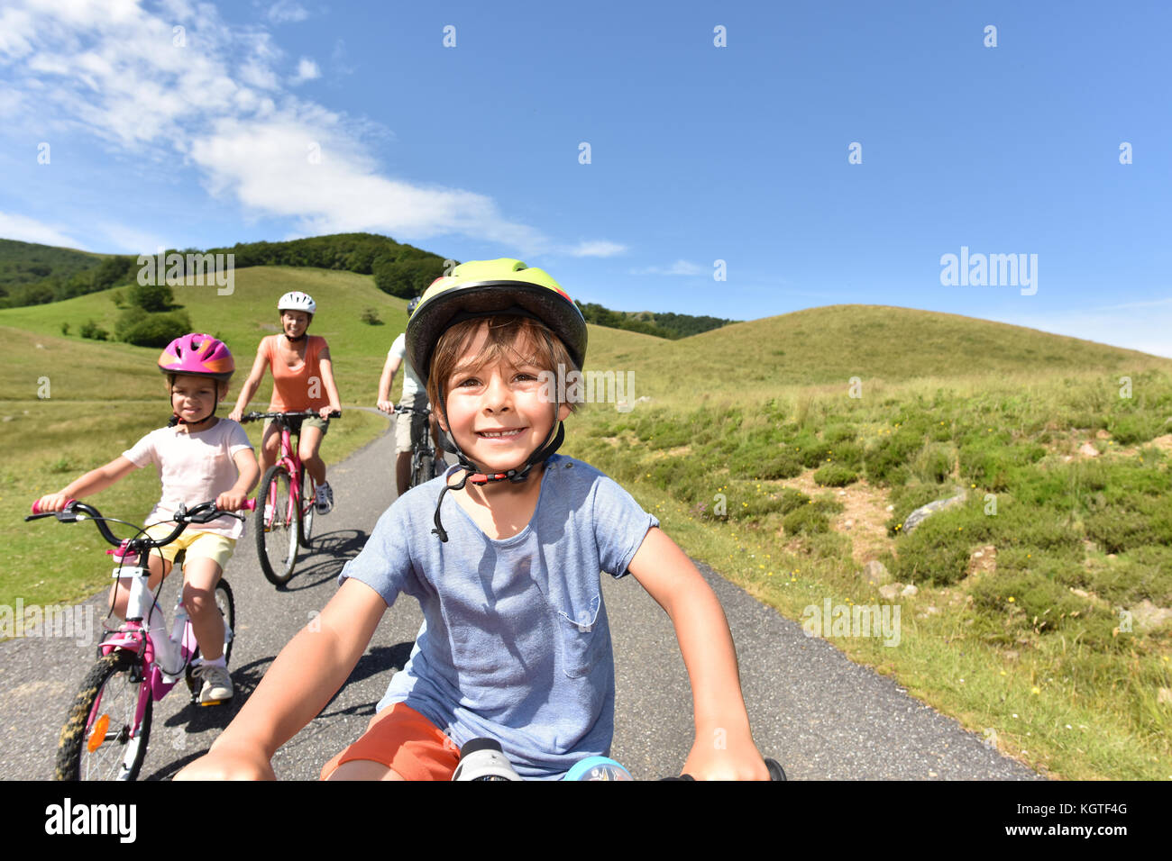 Portrait of little boy riding bike with family Stock Photo - Alamy
