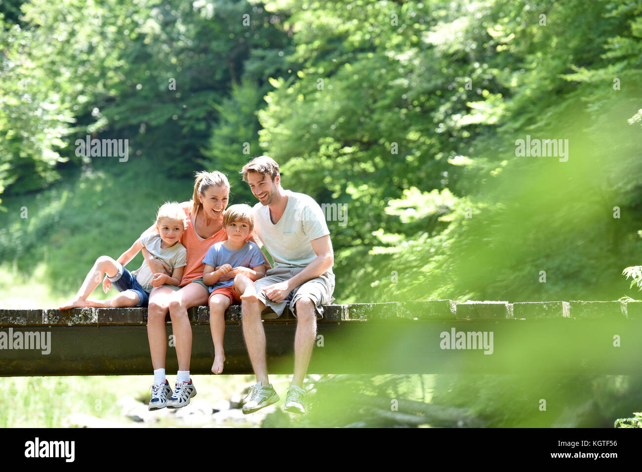 Family sitting on a bridge crossing mountain river Stock Photo - Alamy