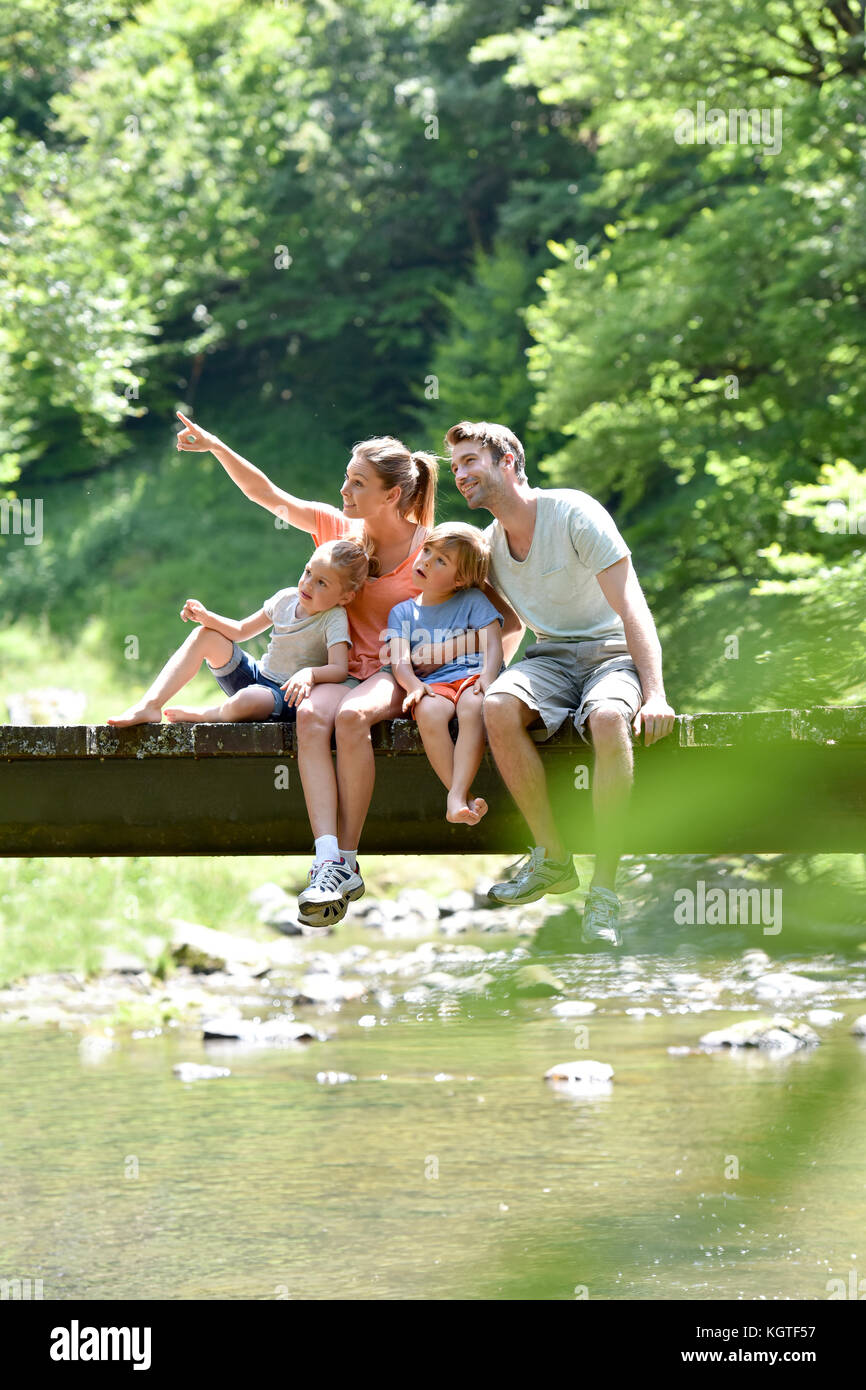 Family sitting on a bridge crossing mountain river Stock Photo - Alamy