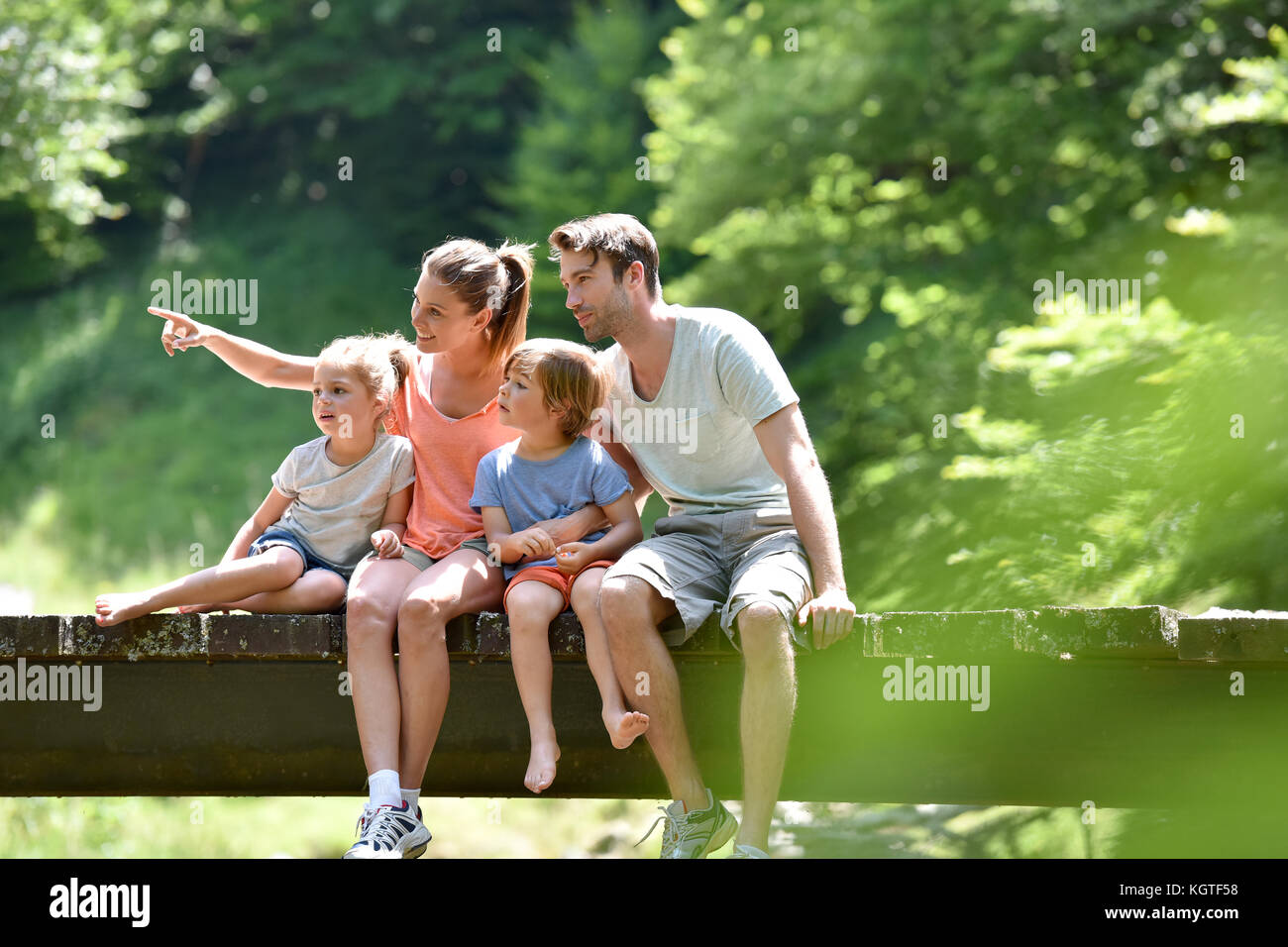 Family sitting on a bridge crossing mountain river Stock Photo - Alamy