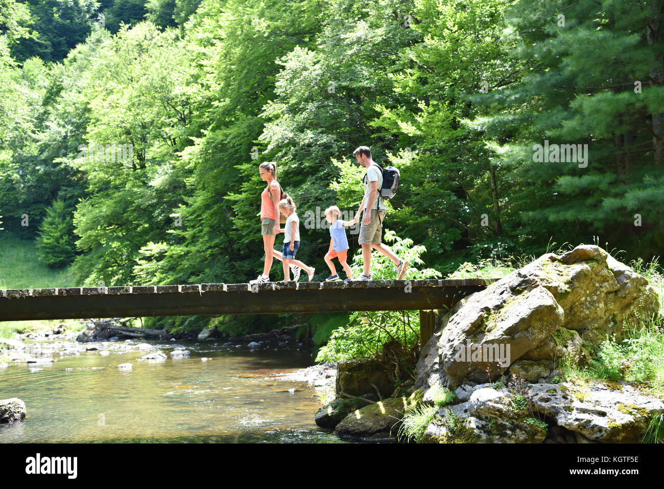 Family of four walking on a bridge crossing the river Stock Photo - Alamy