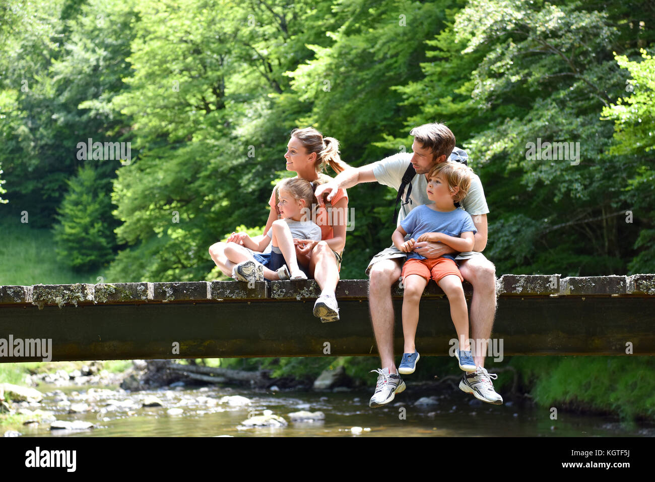 Family sitting on a bridge crossing mountain river Stock Photo - Alamy