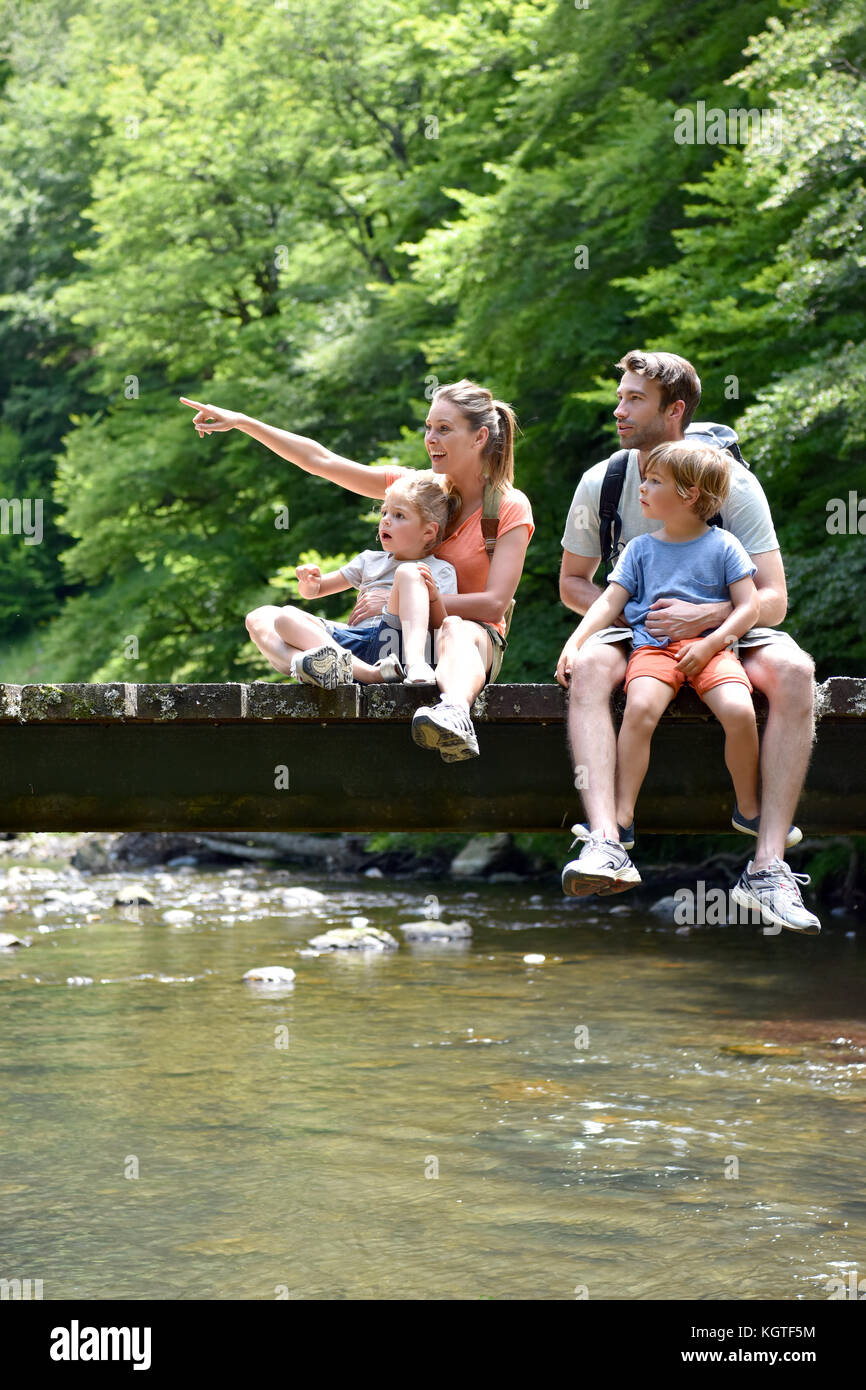 Family sitting on a bridge crossing mountain river Stock Photo - Alamy