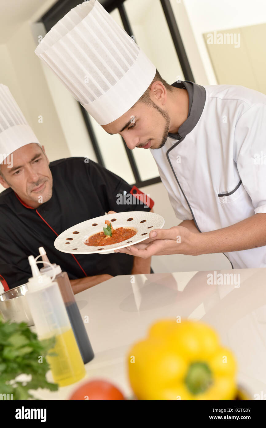 Cook student preparing dish with help of chef Stock Photo - Alamy