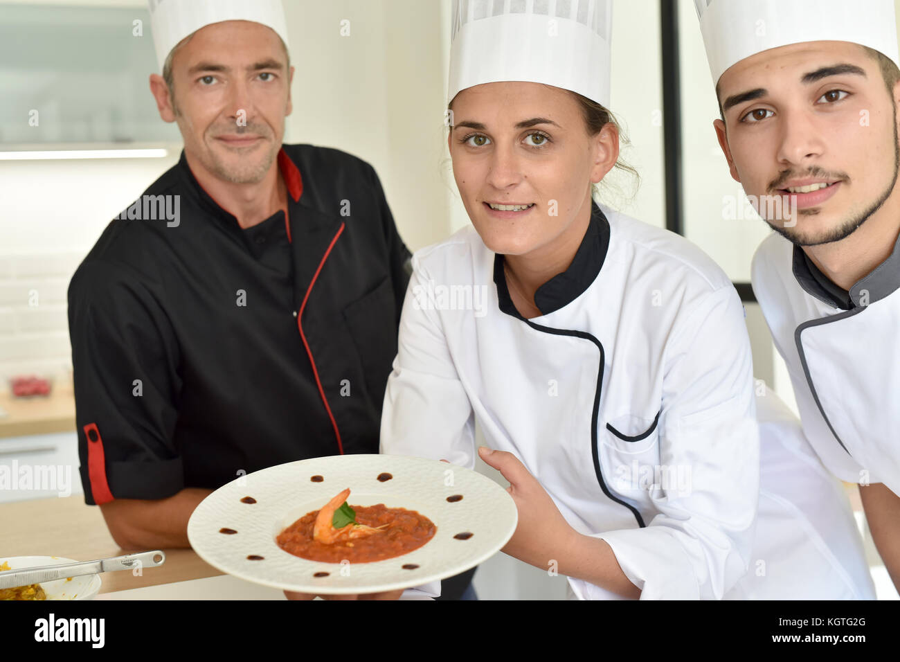 Young chefs presenting dish to teacher Stock Photo - Alamy